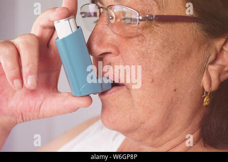 Frau mit einem Aerosol-Inhalator, der Erweiterung der Bronchien zur ...