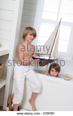 2 Jungs im Bad mit einer Badewanne, das andere ein Modell Boot ...