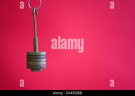 Masses accrochée à un ressort étiré isolé sur un fond rouge. Expérience ...