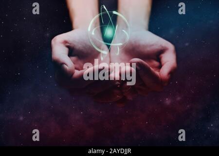 Main humaine tenant atome sur une paume. Poussière de nébuleuse dans un ...