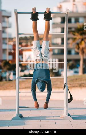 Homme suspendu à l'envers sur la barre horizontale dans anti bottes de ...