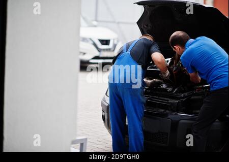 Thème de réparation et d'entretien de voiture. Deux mécaniciens en uniforme travaillant en ...