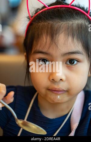 Enfant asiatique femelle tout en mangeant du riz avec une cuillère. L ...