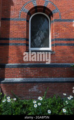 Une fenêtre en verre voûté sur le vieux mur en brique rouge. Fenêtre d ...