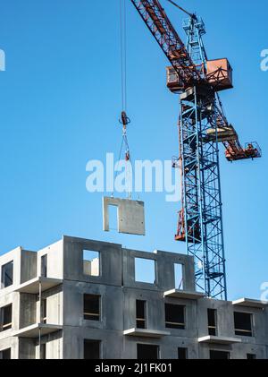 La grue à tour livre une dalle de béton sur un chantier de construction ...