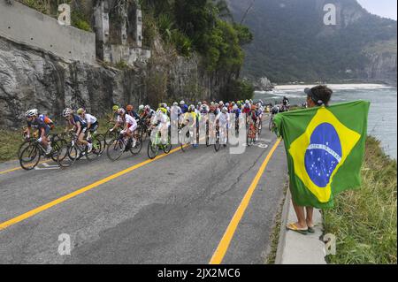 Une femme portant un drapeau brésilien applaudit en tant que coureurs ...