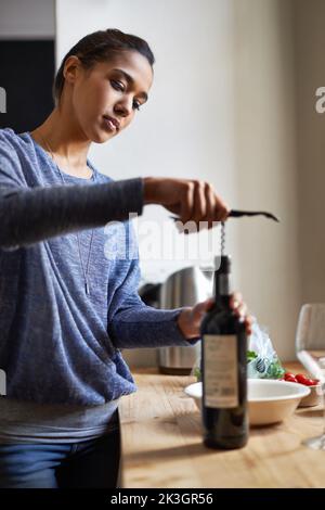 Me verser un peu de vin. Une jeune femme ouvre une bouteille de vin ...