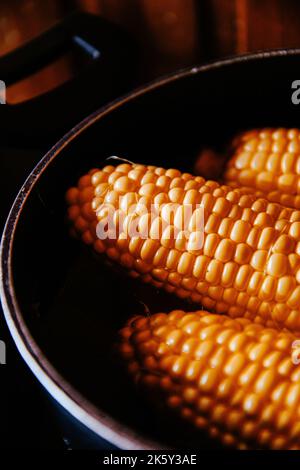 Le maïs juteux orange est bouilli dans de l'eau avec du sel. Maïs dans ...