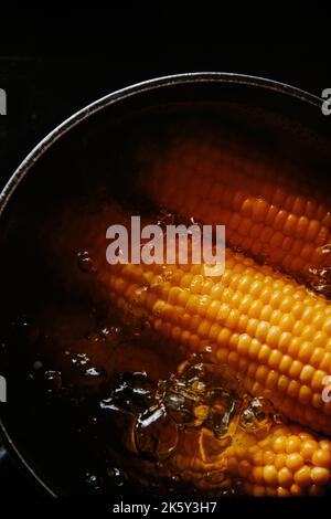 Le maïs juteux orange est bouilli dans de l'eau avec du sel. Maïs dans ...