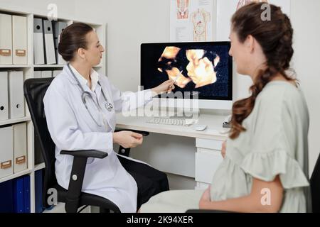 Gynécologue pointant vers un moniteur d'ordinateur avec une analyse de ...