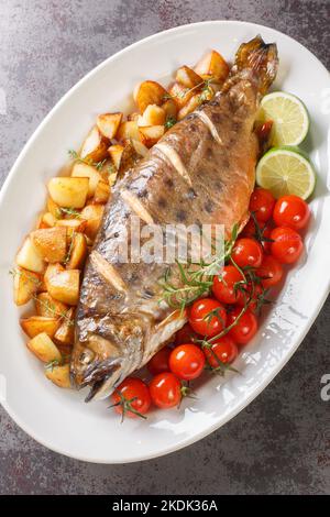Poisson entier cuit au four omble arctique servi avec des pommes de ...