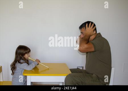 Petite fille jouant la flûte et papa se bouchant ses oreilles. Leçons ...