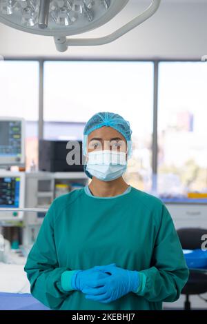 Portrait de la femme chirurgien biracial dans le masque chirurgical, le ...