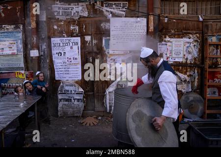 An ultra-Orthodox Jewish man dips cooking utensils in boiling water to ...