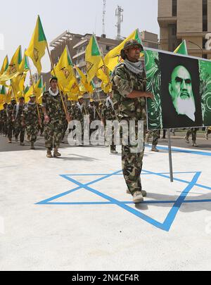 Supporters of Iraqi Hezbollah brigades marching in military uniforms ...