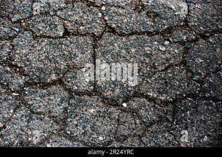 Un réseau de fissures noires sur la surface de l'asphalte. Texture de ...