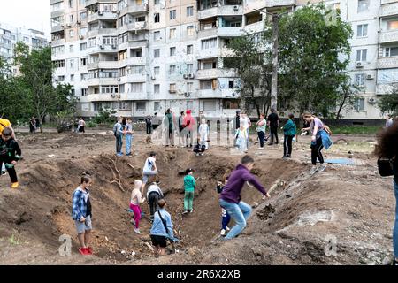 Les enfants jouent dans un cratère près du bâtiment résidentiel détruit ...