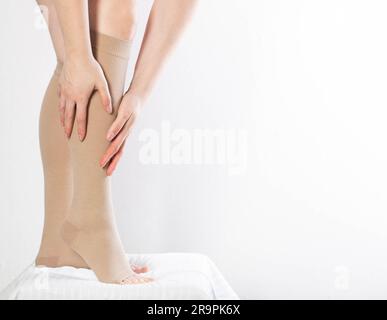 Une femme met des bas de contention pour les jambes aux varices ...