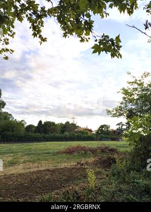 Champ et maisons bordés par une tranchée avec eau et arbres au coucher ...