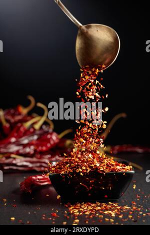 Les flocons de piment sont versés dans un plat noir. Flocons de piment ...