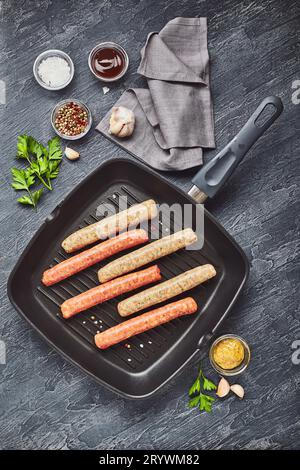 Saucisses de boeuf cru sur un poêle en fonte avec le romarin et d'épices sur une table en bois ...