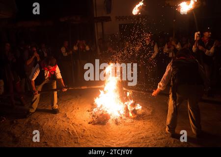 On voit des villageois allumer une torche sur un feu de joie à l ...