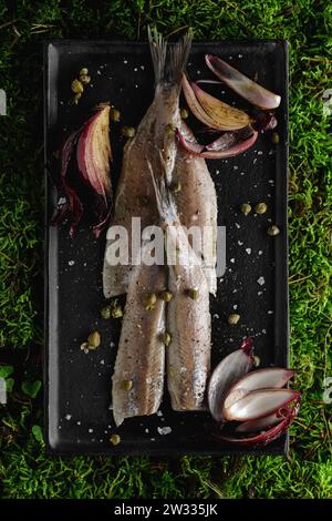 Filet de hareng avec câpres, flocons de sel et poivre servi sur plateau ...