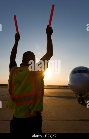 Avion est guidé par un travailleur de l'aéroport à l'aérogare à l ...