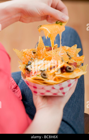 En tenant la main tortilla chip au fromage fondu de la plaque Photo ...