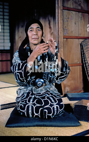 Une femme Ainu âgée sur l'île d'Hokkaido dans le nord du Japon montre ...