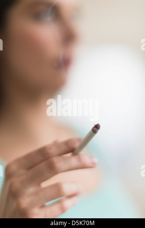 Une femme latine fumeurs, tenant une cigarette avec son doigt et sa ...