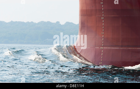 La proue d'un grand cargo qui pousse dans l'eau et traverse un bateau à ...