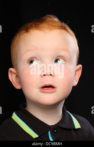 Portrait d'un garçon roux avec des taches de rousseur sur un fond noir ...