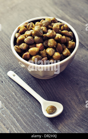Les câpres dans un bol en bois sur fond blanc. Les boutons de fleurs ...