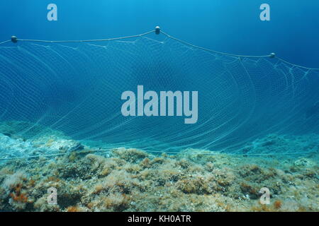 Sous l'eau un filet de pêche (filet maillant) fixé sur les roches au ...