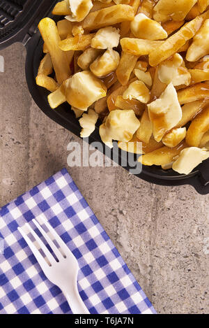 La poutine dans un récipient pour emporter. Cuite avec des frites, du ...