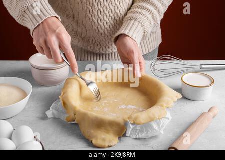 Donna che usa la forchetta per incatenare i fori su tutta la pasta sul ...
