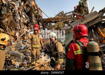 Iranian firefighters work at the scene of the collapsed Plasco building ...