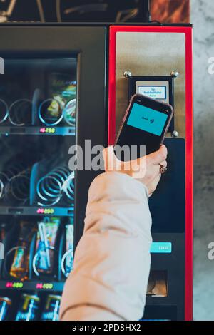 Il consumatore paga il prodotto al distributore automatico utilizzando il metodo di pagamento ...