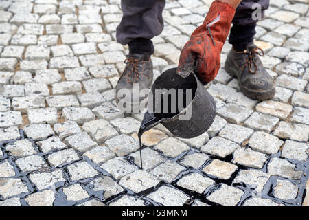 Versando passo fuso da un secchio di catrame. Passo tradizionale per ...