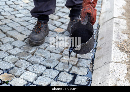Versando passo fuso da un secchio di catrame. Passo tradizionale per ...